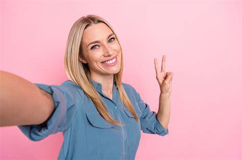 쾌활한 이빨이 빛나는 여자 긴 헤어 스타일을 입은 푸른 셔츠를 만드는 사진 분홍색 배경에 고립 된 V 기호를 보여주는 셀카 만들기 35 39세에 대한 스톡 사진 및 기타