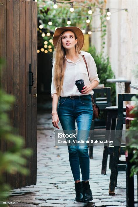 이동 중커피 한 잔과 함께 구시 가지의 거리를 따라 걷는 캐주얼 스타일의 옷을 입은 젊은 매력적인 여성 갈란드 장식품에 대한 스톡 사진 및 기타 이미지 Istock