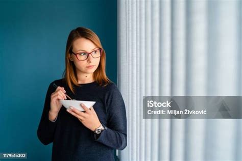 뮤즐리 또는 수프 식사와 함께 그릇을 들고 안경을 가진 젊은 여성은 집에서 창으로 먹는 숟가락이나 직장에서 쓰루 아침 식사 점심을 보고 가정 생활에 대한 스톡 사진 및 기타