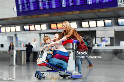 공항에서 두 어린 아이 소년과 소녀 형제 자매와 어머니 어린이 가족 여행 비행기로 휴가를 가고 비행기를 타기 위해 터미널에서 여성이 밀어내는 여행 가방을 들고 트롤리를
