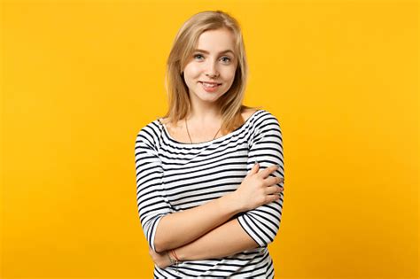 스튜디오에서 노란 주황색 배경에 고립 된 교차 된 카메라를 들고 보이는 줄무늬 옷에 아름 다운 젊은 여자의 초상화 사람들은 진심으로 감정 라이프 스타일 개념입니다 복사