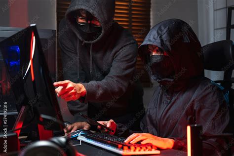 dangerous hooded hacker typing bad data into computer online system and