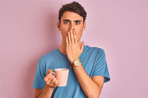 고립된 분홍색 배경 커버 입위에 커피 한 잔을 마시는 십대 소년은 실수 두려움의 표현 침묵 비밀 개념에 대한 수치심으로 충격을 받았습니다 가리기에 대한 스톡 사진 및 기타