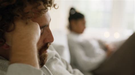 Man Reading Book And Woman Scrolling On Smartphone Both Sitting On Sofa 4427154 Stock Video At