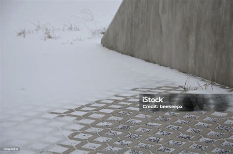 잔디 회색 콘크리트 타일은 부분적으로만 눈이 내렸습니다 포장은 자갈로 가득합니다 옹회색 벽의 투과성 경로 또는 주차장역할을 합니다 드론의 측면 보기 포장용 석재에 대한 스톡