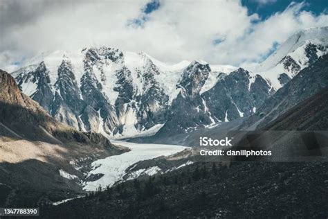 흐린 하늘에 햇빛에 빙하 혀와 큰 눈 덮인 산아름다운 산 풍경 빙하 혀와 낮은 구름에 빙하가있는 높은 산이있는 아름다운 고산 풍경 경관에 대한 스톡 사진 및 기타 이미지