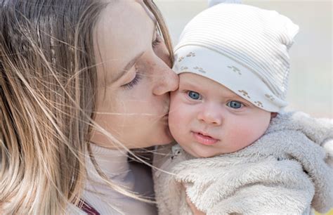 한 젊은 어머니가 매력적인 어린 아들을 품에 안고 있습니다 아이는 카메라를보고 미소 지었다 아름다운 통통한 4개월 된 아기의