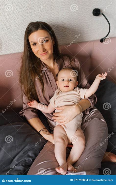 Happy Mother Holds A Baby Baby In Her Arms Smiling Sitting On The Bed Stock Photo Image Of
