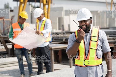 초상화 아프리카계 미국인 엔지니어 남자는 서류 작업과 프리캐스트 시멘트 공장 배경으로 작업하는 팀과 함께 워키토키를 사용합니다 25 29세에 대한 스톡 사진 및 기타 이미지