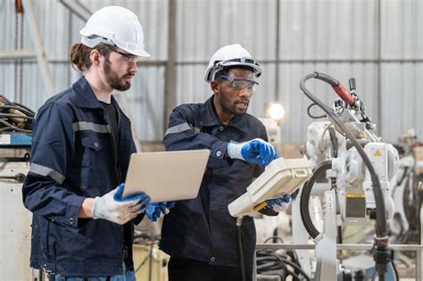 Engenheiros do sexo masculino usando laptop e máquina de solda de braço de robô de inspeção de