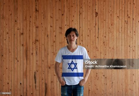남자 이스라엘 국기 색상 셔츠를 입고 나무 벽 배경에 바지 주머니에 두 손으로 서 T 셔츠에 대한 스톡 사진 및 기타 이미지