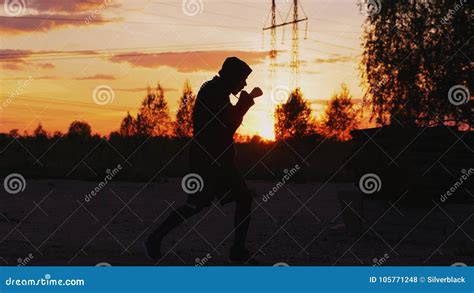 Silhouette Of Young Man Boxer Training For Kicking On Sunset At City