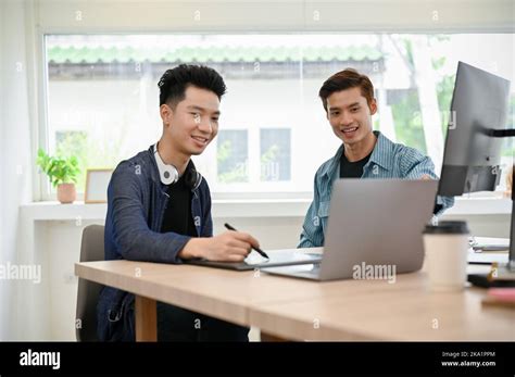 Two Professional Young Asian Male Programmers Or Photo Editors Working