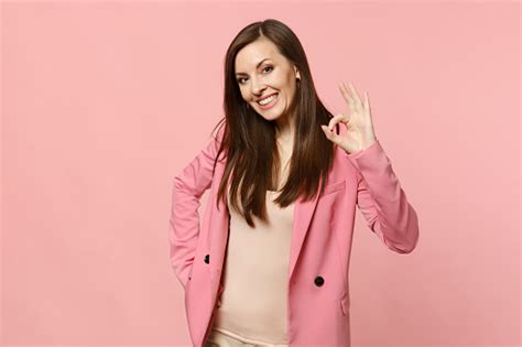 스튜디오에서 파스텔 분홍색 벽 배경에 고립 된 확인 제스처를 보여주는 재킷에 아름 다운 젊은 여자를 웃 고의 초상화 사람들은 진심으로 감정 라이프 스타일 개념입니다 복사