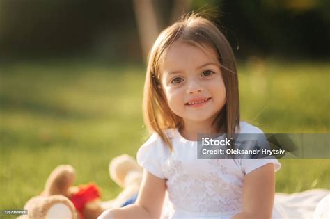 사랑스러운 어린 소녀의 클로즈업은 야외에서 격자 무늬에 앉아 책을 읽습니다 행복한 미소 아기 소녀는 일몰에 뒤뜰에 시간을 보내고