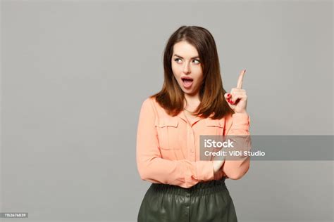 파스텔 캐주얼 옷 옆에 보이는 젊은 여자를 깜짝 놀라게 회색 벽 배경에 고립 된 좋은 새로운 아이디어와 인덱스 손가락을 들고