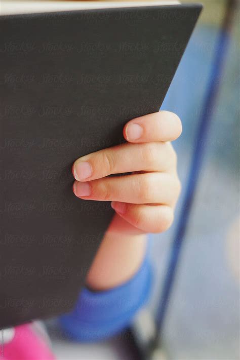 A Young Girls Fingers Grip The Edge Of The Book Shes Reading By