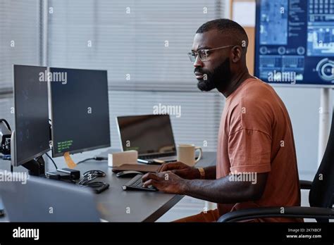 Side View Of Black Software Engineer Using Computer In High Technology Office Data Systems And