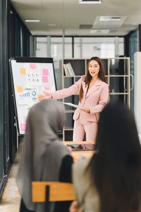 Confident Businesswoman Presenting Data Charts And Graphs During An Office Meeting Stock Photo