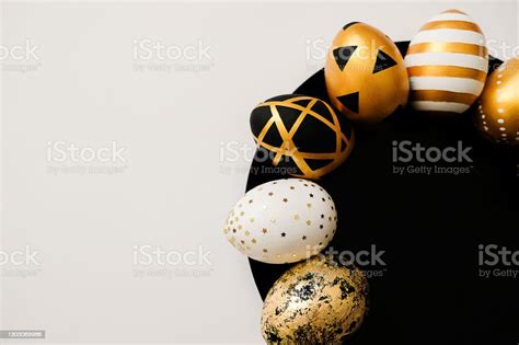 흰색 배경에 고립 된 검은 접시에 세련된 부활절 황금 장식 계란 트렌디 한 플랫 평신도 부활절 텍스트에 대한 복사 공간이있는 행복한 부활절 카드 최소한의 부활절 개념 4월에