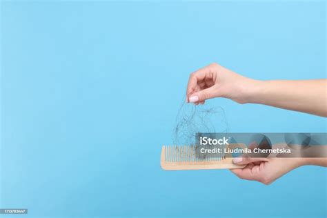 연한 파란색 배경에 빗에서 잃어버린 머리카락을 풀고 클로즈업과 텍스트를 위한 공간을 마련하는 여자 탈모증 문제 건강관리와 의술에