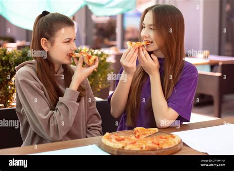 Two Teen Girls Eating Pizza In Cafe Outdoors After Classes Two Friends