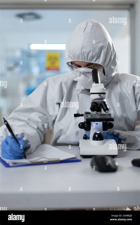 Biologist Researcher Wearing Protective Suit Analyzing Chemicals Using Medical Microscope While