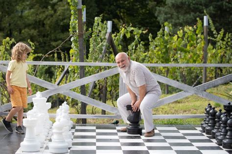 дедушка и внук играют в шахматы на большой шахматной доске поколения Стоковое Изображение