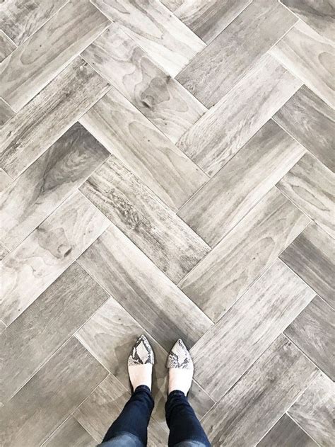 A Person Standing On Top Of A Wooden Floor Next To A White Wall And Gray Tile