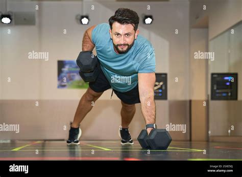 Athletic Man Performing A Plank Row With Dumbbells In A Gym Demonstrating Strength And Balance