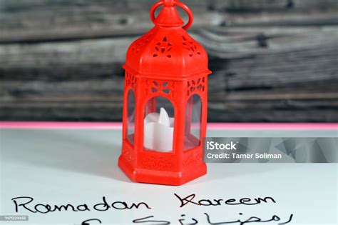 아랍어와 영어로 된 라마단 카림 텍스트는 Fanous 등불 램프 초승달 및 별에 의해 축제되는 무슬림을위한 금식 달의 축제 장식으로 보드에 손으로 쓰여졌습니다 Eid Ul