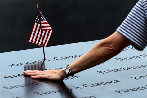 A Woman Places Her Hand Over A Name On The Memorial At The National