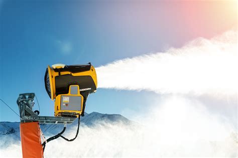 눈가루를 만드는 피스트 근처에서 인공 눈 대포를 작동합니다 화창한 날에 힐랜드 알프스 산 겨울 리조트의 스키 리프트 로프웨이