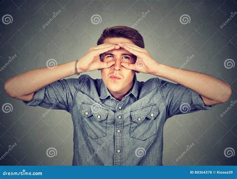 Раздражанный молодой человек смотря через пальцы любит бинокли Стоковое Фото изображение