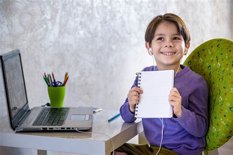 원격 학습 온라인 교육 집에서 공부하는 남학생 소년이 종이 수첩을 손에 쥐고 있는 학교 숙제를 하고 있습니다 홈 거리 학습 가정 생활에 대한 스톡 사진 및 기타 이미지