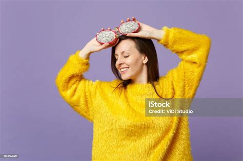 모피 스웨터에 편안한 젊은 여자는 피 야 하 야의 Halfs 개최 보라색 파스텔 배경에 고립 된 드래곤 과일을 들고 유지 합니다
