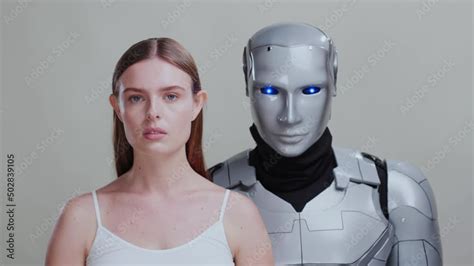 Portrait Couple Of Babe Caucasian Woman And Robotic Cyborg With Blue Eyes Posing For Grey