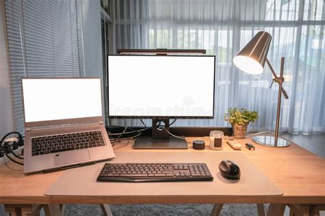 Computer Device With Blank Monitor Laptop Table Lamp Keyboard Mouse On Wooden Desk In Home