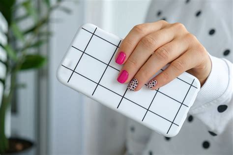 휴대 전화를 들고 세련된 분홍색 손톱으로 손질 된 여성의 손 스마트 폰 기술 트렌디 한 현대 디자인 매니큐어 젤 손톱 스킨 케어 뷰티 트리트먼트 네일 케어 트렌디한 색상