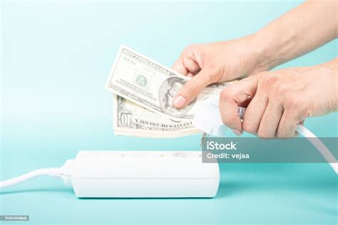 파란색 배경에 파워 스트립 연장 코드 근처의 전력 플러그와 미국 달러 지폐를 들고있는 여성 손 전기 비용 전기 가격 인상 값 비싼 에너지 개념 0명에 대한 스톡 사진 및