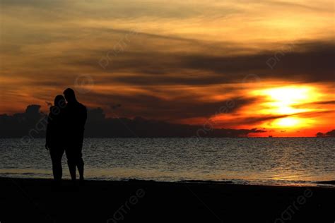 Silhouette Of Romantic Honeymoon Couple Walking On The Beach With