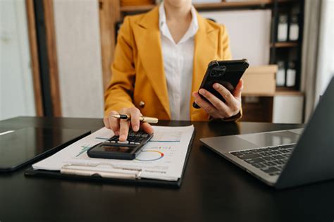 돼지 저금통에서 계산기로 동전을 세는 여자들 사무실에서 비용에 대해 책상에서 계산하기 위해 계산기 작업을 하는 펜을 들고 있다 개념에 대한 스톡 사진 및 기타 이미지