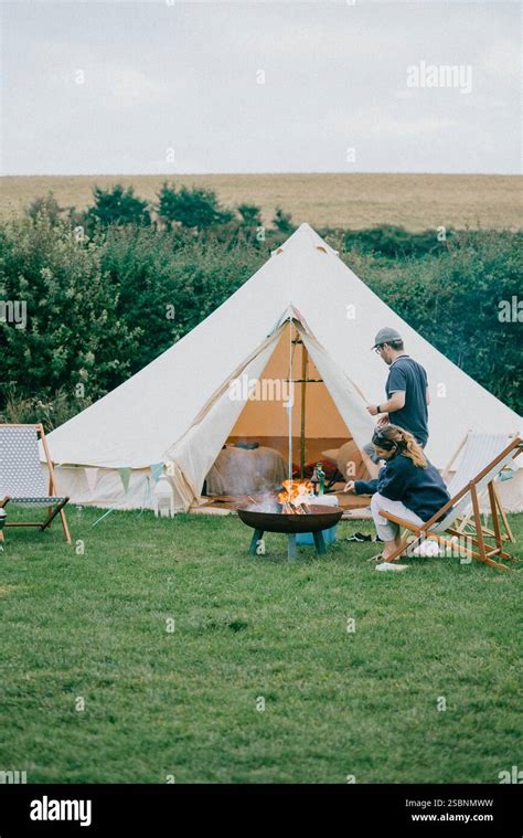 A Man And Woman Are Sitting In A Teepee With A Fire In The Middle The