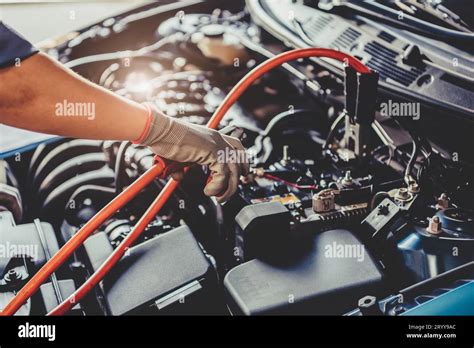 Car Mechanic Holding Battery Electricity Trough Cables Jumper And Checking To Maintenance