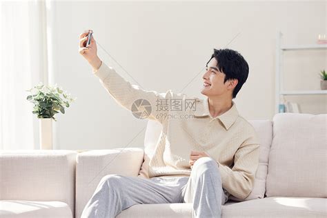 坐在客厅休息的年轻人使用手机自拍高清图片下载 正版图片507696413 摄图网