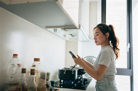 젊은 아시아 여성 아침 식사 준비 및 국내 주방에서 휴대 전화 사용 30 34세에 대한 스톡 사진 및 기타 이미지 30 34세 Brand Name Smart Phone