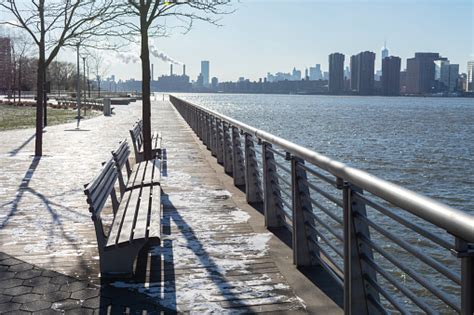 맨해튼 스카이라인을 바라보는 롱아일랜드 시티 퀸즈 뉴욕의 이스트 리버를 따라 비어 있는 벤치 0명에 대한 스톡 사진 및 기타