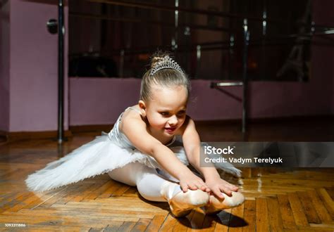 나무 바닥에 앉아 신발 그녀의 포인트를 스트레칭 흰색 발레 용 스커트를 입고 매력적인 젊은 발레리 나 Performing Arts Event에 대한 스톡 사진 및 기타