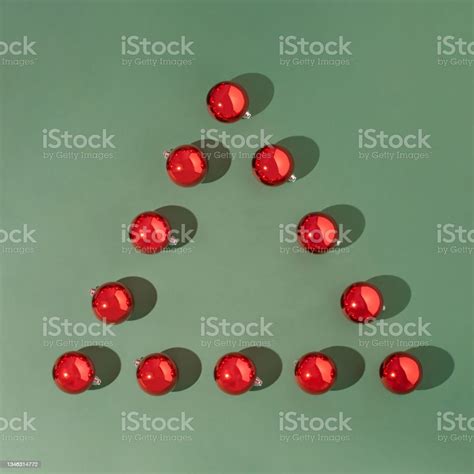 녹색 배경에 빨간색 크리스마스 Baubles로 만든 삼각형 프레임 최소한의 새해 개념 크리에이티브 카피 공간 홀리데이 플랫 레이 미학 화창한 날 그림자 12월에 대한 스톡