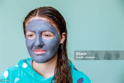 스파 여자 얼굴 클레이 마스크를 적용입니다 미용 치료입니다 페이셜 마스크를 적용 하는 그녀의 머리에 수건으로 아름 다운 여자의 클로즈업 초상화 가꿔주기에 대한 스톡 사진 및